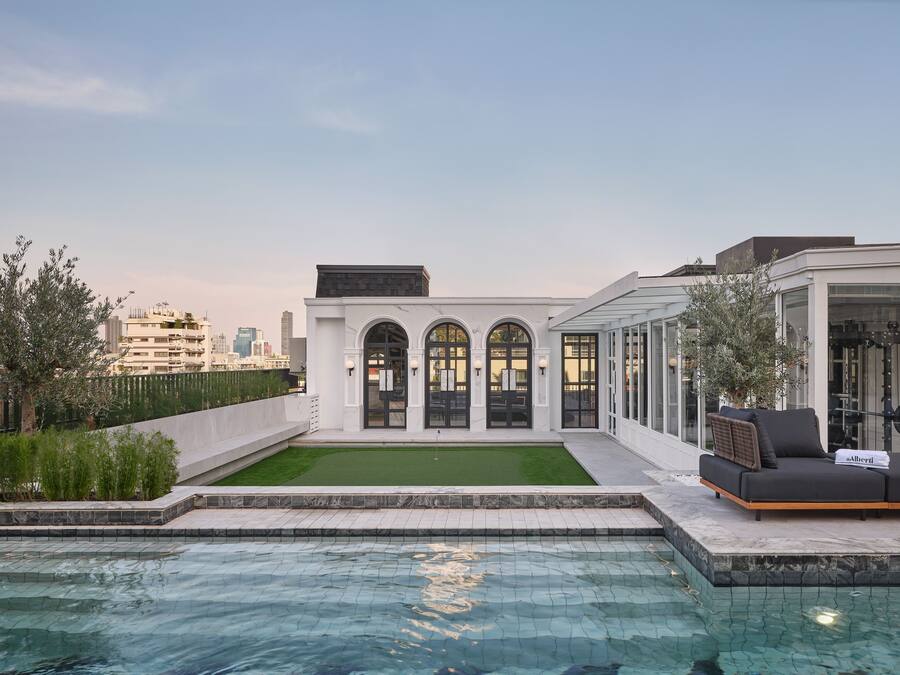 Uma área de piscina no terraço com um edifício moderno, um espaço para sentar e vista para o horizonte da cidade.