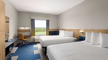 Quarto de hotel com duas camas, uma escrivaninha, uma cadeira e uma janela com vista.