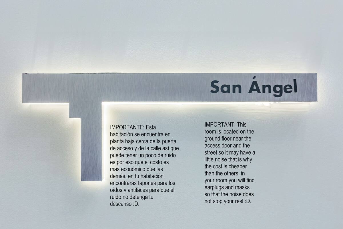 Placa na parede com o nome 'San Ángel' e texto descrevendo a localização e comodidades do quarto.