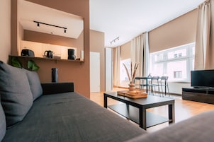 Uma sala de estar moderna com sofá, mesa de centro, televisão e área de jantar com cadeiras e mesa.