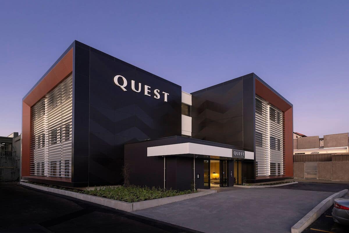 Um edifício moderno com o nome 'QUEST' em destaque na fachada.