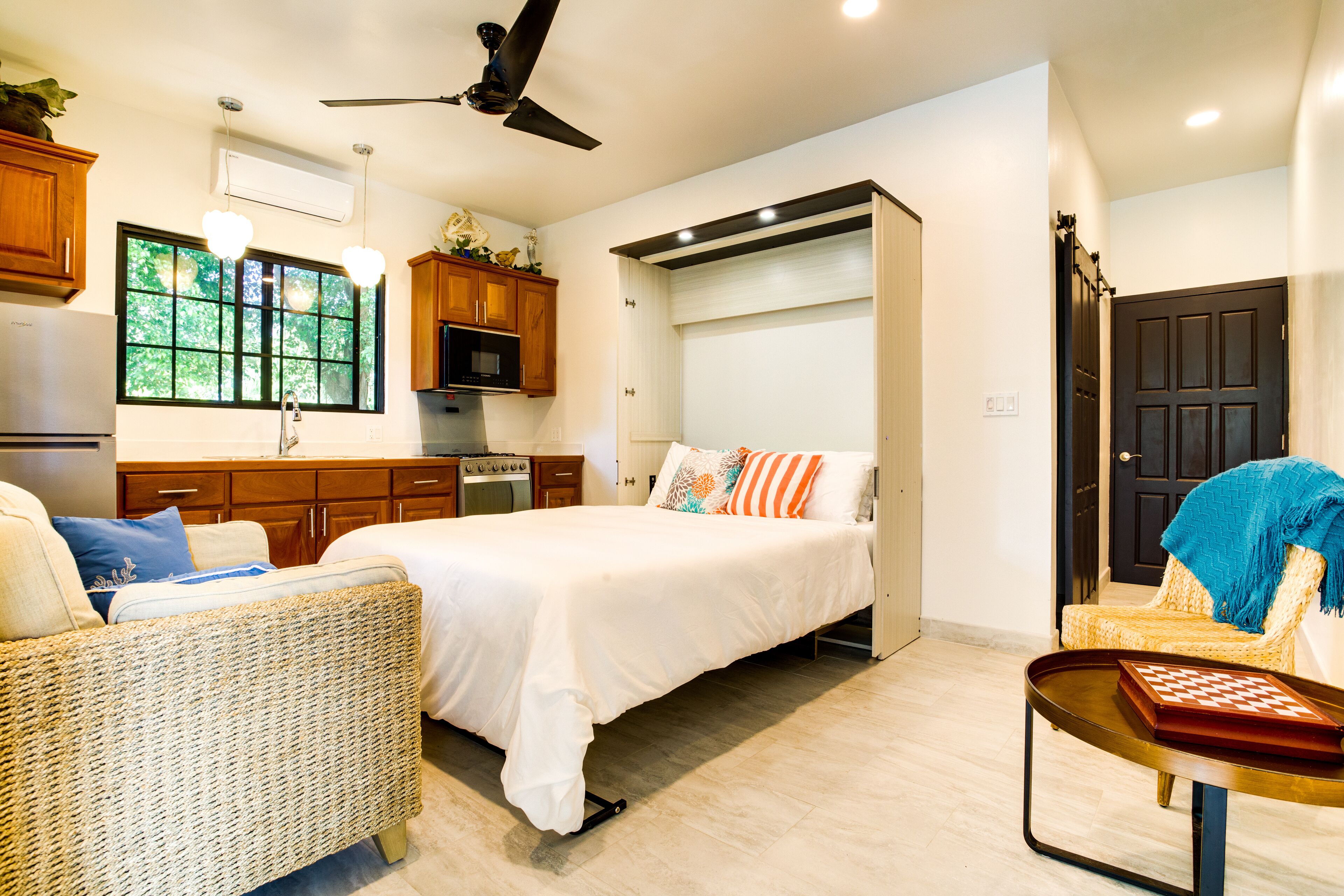 Quarto com cama, cadeira, mesa e ventilador de teto.