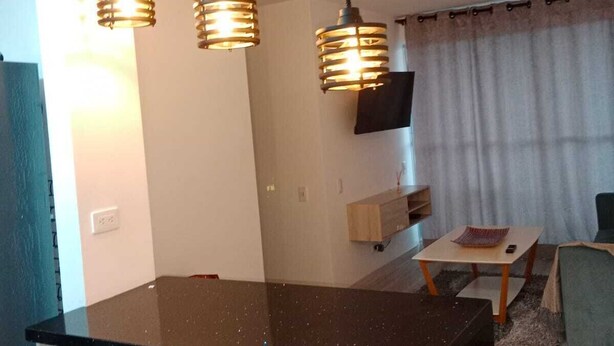 Cozinha moderna com bancada preta e três luminárias pendentes.