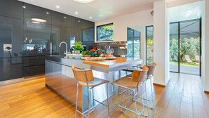 Cozinha moderna com ilha central, banquetas e vista para o exterior.