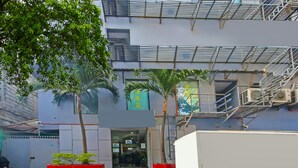 Um edifício com escadaria que leva a uma entrada, cercado por vasos vermelhos e uma caminhonete branca estacionada.
