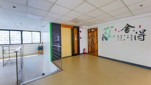 Um corredor amplo com piso de azulejos, escada com corrimão de metal e porta de madeira com painel decorativo.