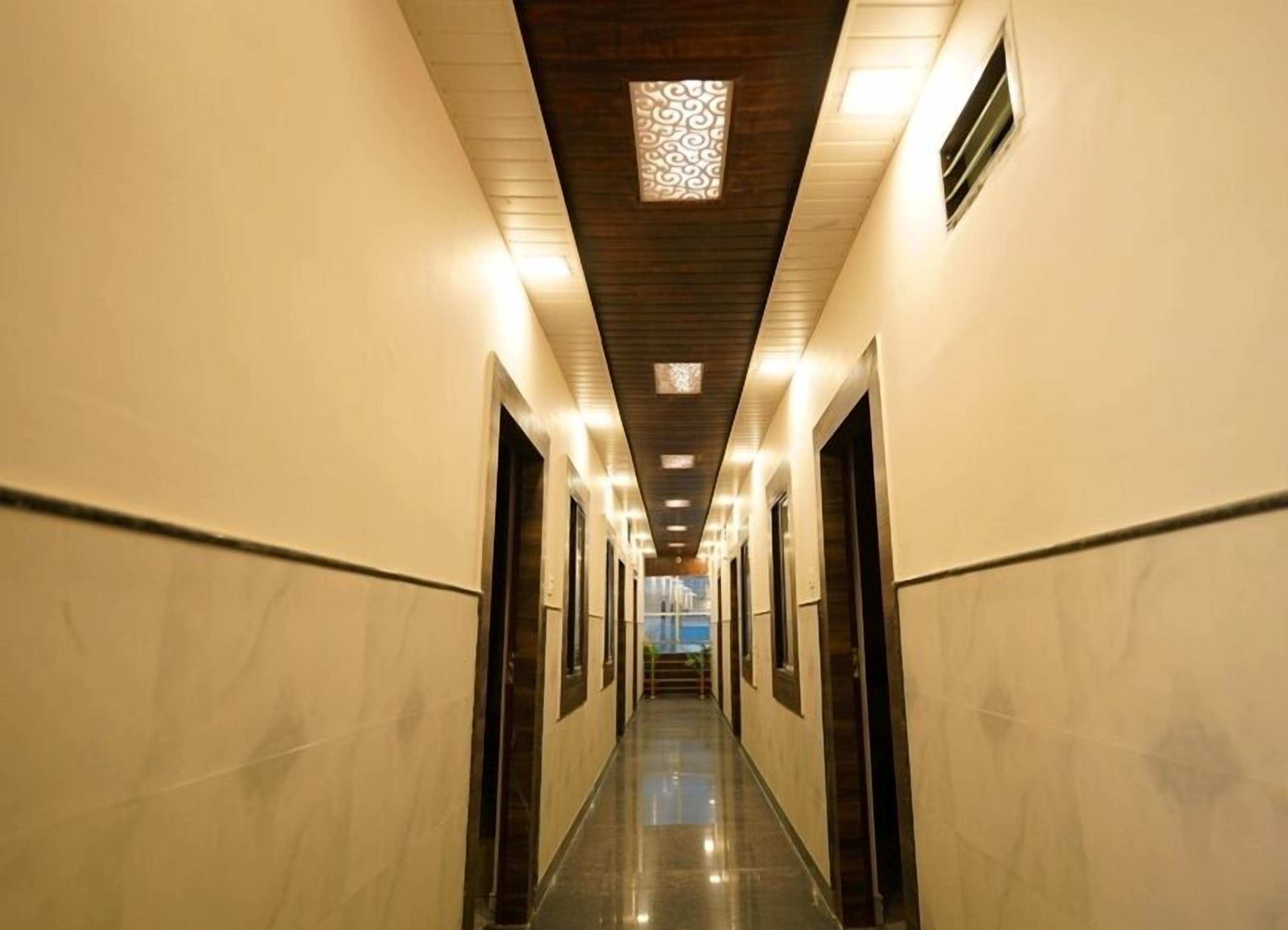 Corredor longo e bem iluminado, com piso refletivo, que leva a uma porta no final.