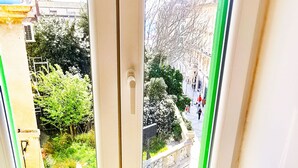 Uma janela com vista para a rua e um pequeno jardim.