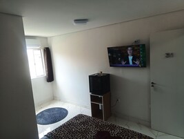 Quarto com televisão na parede, uma mesinha, sofá com estampa de leopardo e porta com o número 31.