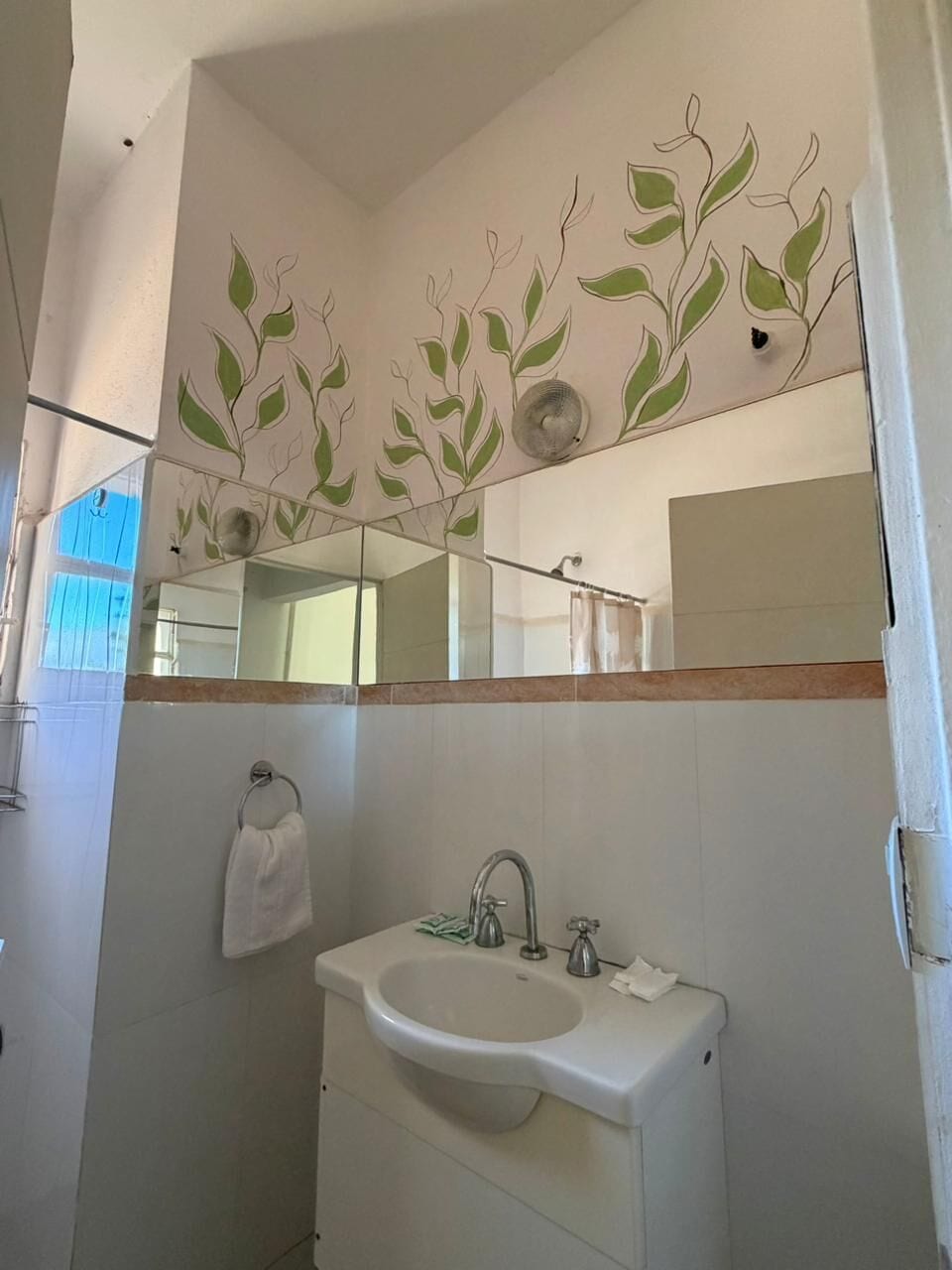 Casa de banho com lavatório, espelho e decoração na parede.