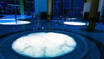 Área de piscina ao ar livre com hidromassagens e uma piscina central aquecida.