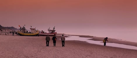 Uma praia com um barco e pessoas.