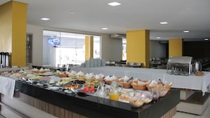 Buffet com diversos alimentos e bebidas, uma tela de televisão e design de interiores moderno.