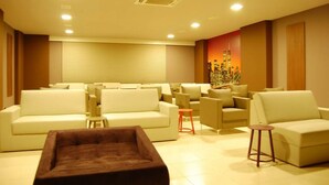 Uma sala de cinema moderna com fileiras de sofás brancos e um banquinho marrom.