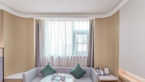 Quarto de hotel moderno com sofá, uma mesa redonda pequena e uma mesa de cabeceira.