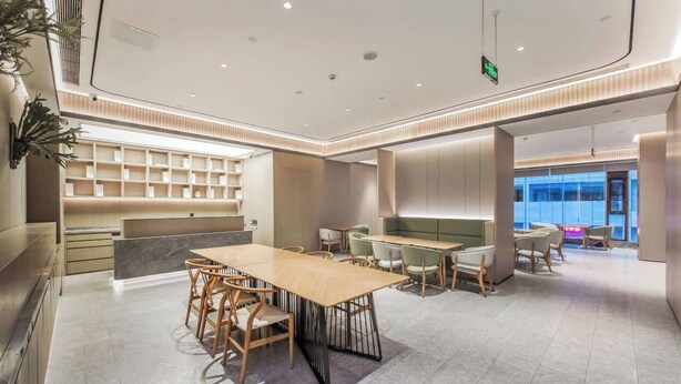 Um lobby de hotel moderno com área de estar central, balcão de recepção e vista para o exterior.