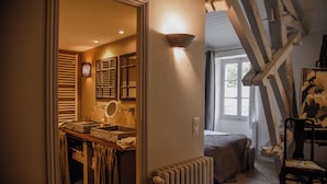 Quarto com cama, radiador, cadeira e janela.
