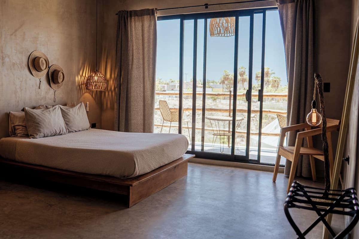 Quarto com uma cama grande, duas luminárias fixadas na parede e vista para o exterior.