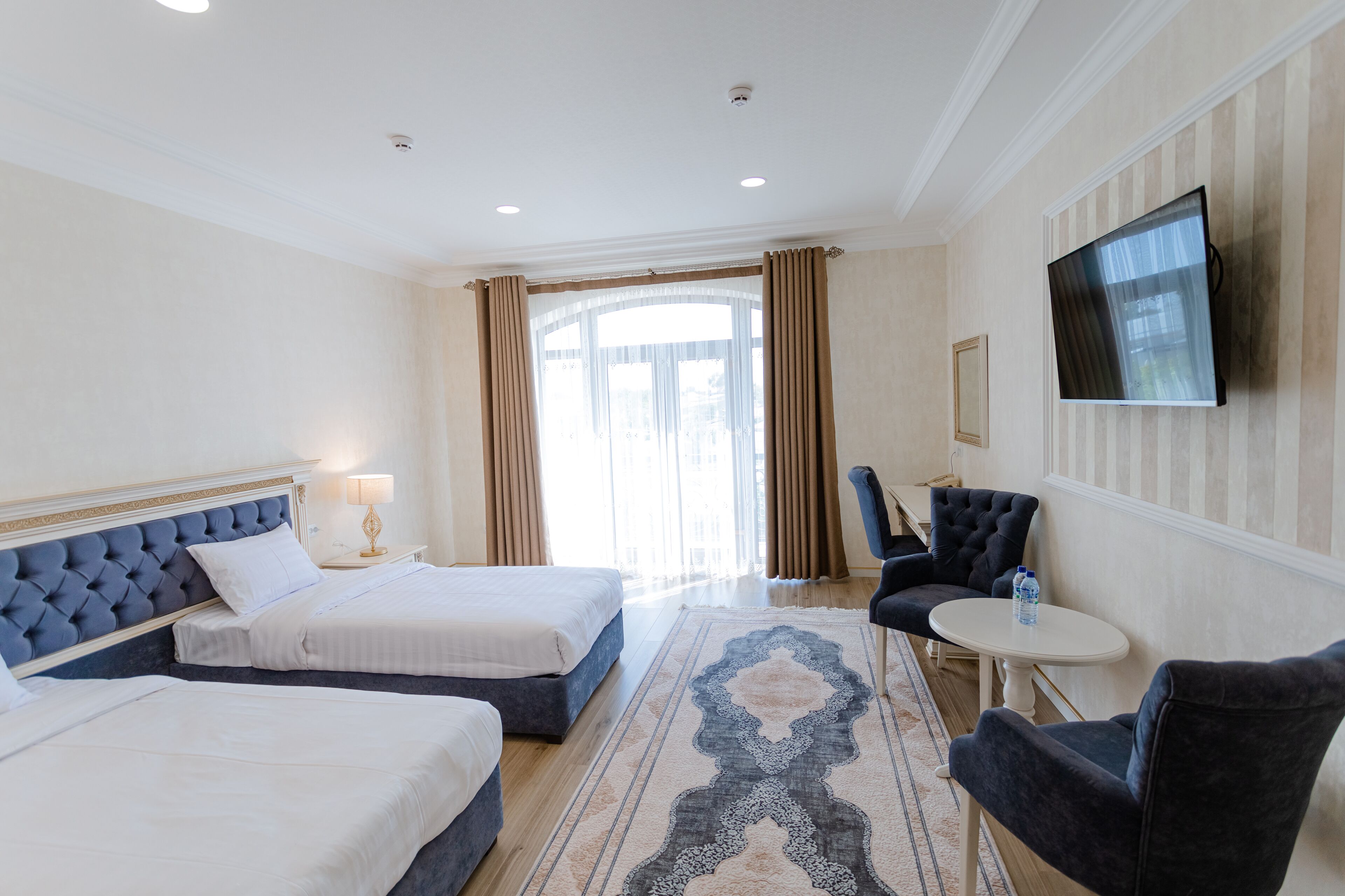 Quarto de hotel com duas camas, uma televisão, uma mesinha e uma cadeira.