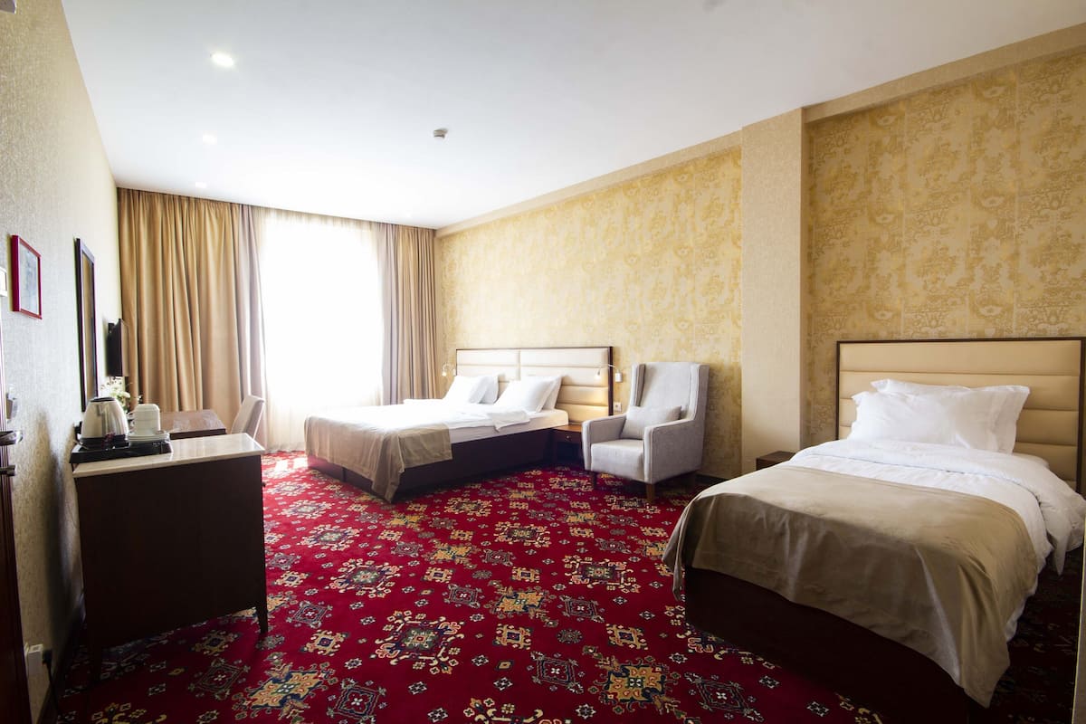 Quarto de hotel com duas camas, uma mesa e uma cadeira.