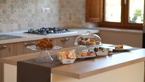 Uma bancada de cozinha com doces, um canto para café e uma vitrine de sobremesas.