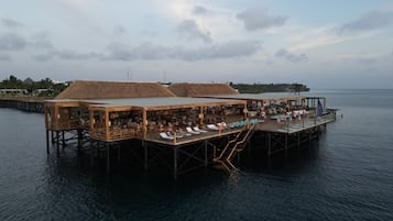 Uma estrutura flutuante com vários níveis, incluindo área de refeições e um lounge com espreguiçadeiras.