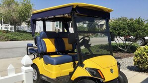 Um carrinho de golfe amarelo estacionado na calçada.