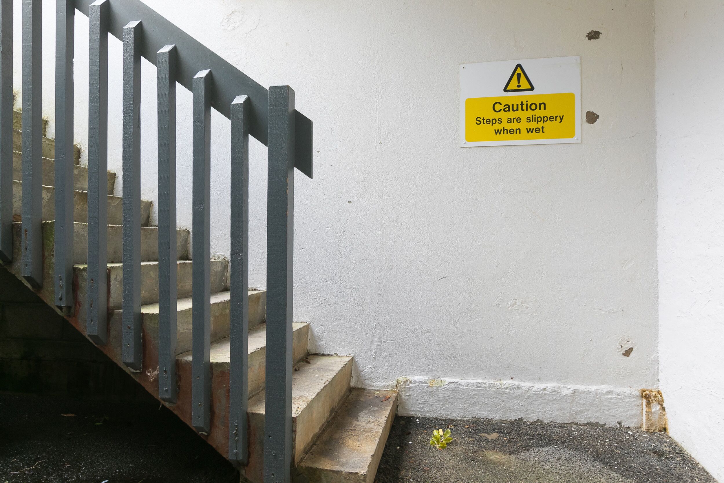 Escadaria com sinal de alerta indicando que os degraus são escorregadios quando molhados.