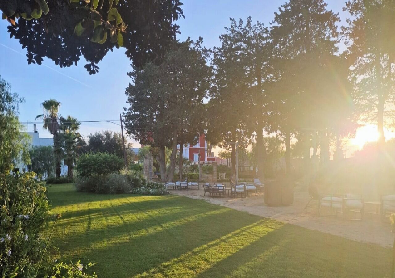 Um jardim bem cuidado com um espaço de pátio, mobiliário de exterior e um edifício ao fundo.