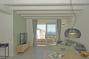 Uma sala de estar moderna com televisão, sofá e mesa de jantar.