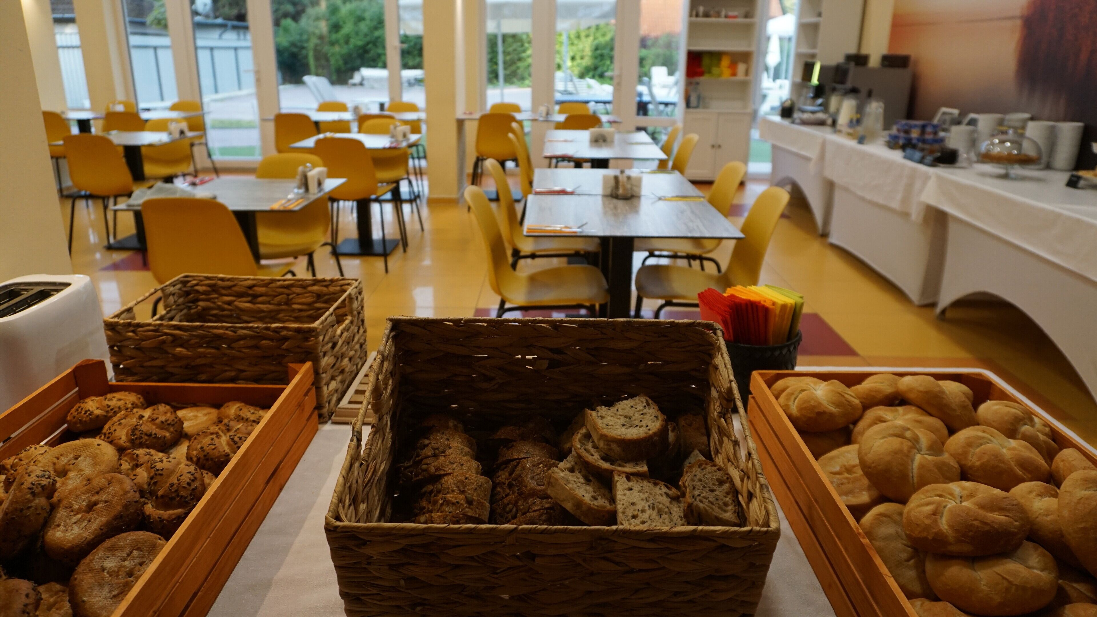 Uma área de buffet com diversos pães e doces dispostos em cestas.