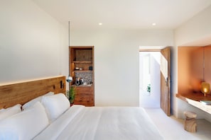 Quarto moderno com cama grande, cabeceira de madeira, estantes embutidas e um pequeno espaço de trabalho.