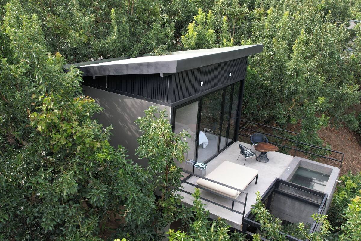 Um terraço moderno ao ar livre com design minimalista, com área de estar com mesa e cadeiras, rodeado por vegetação exuberante.