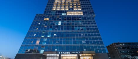 Um hotel moderno com fachada de vidro, entrada imponente e uma placa com a inscrição 'CRYSTAL'.