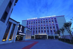 Hotel com fachada moderna, vários andares e entrada com tapete vermelho.