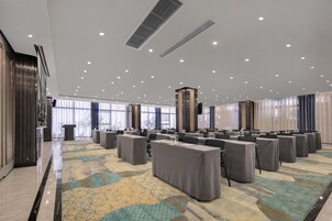 Uma sala de conferências com várias mesas, carpete estampado e design moderno no teto.