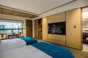 Quarto de hotel com duas camas, televisão, escrivaninha e janela com vista.