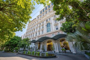 Um hotel de vários andares com fachada clássica, janelas amplas e entrada central com marquise.