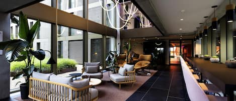 Um lobby moderno com área de estar, janelas amplas e um balcão extenso.
