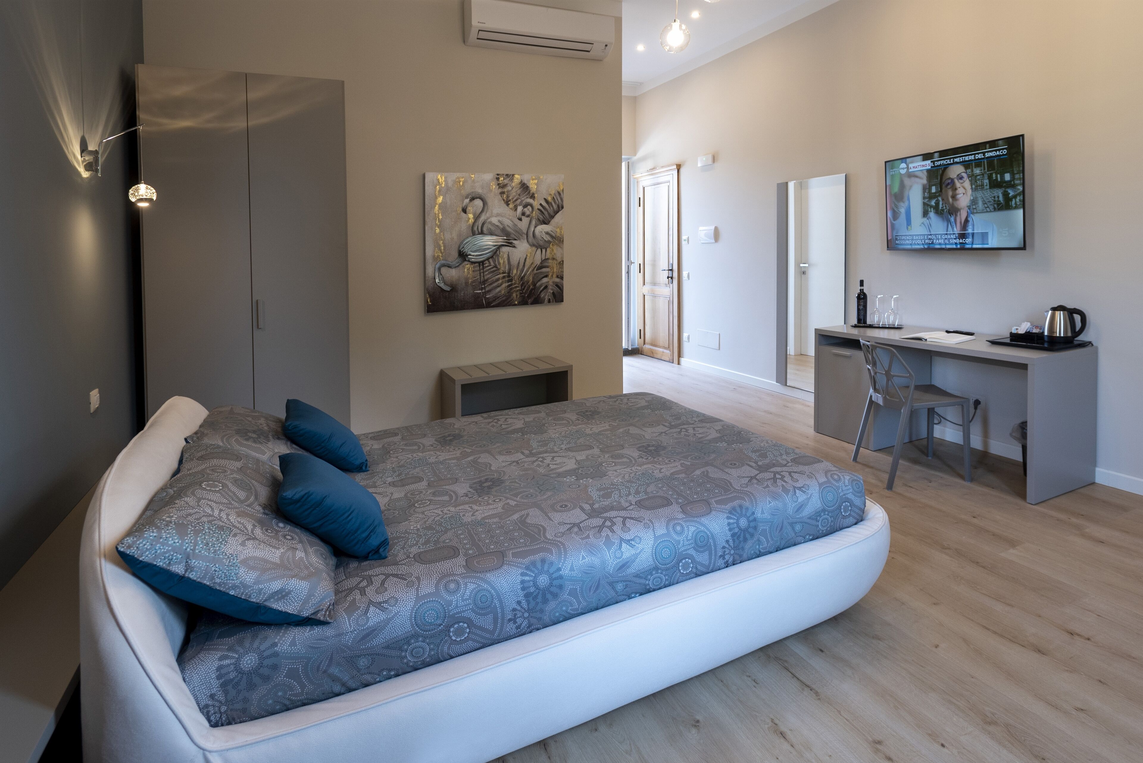 Quarto moderno com cama, escrivaninha e televisão.