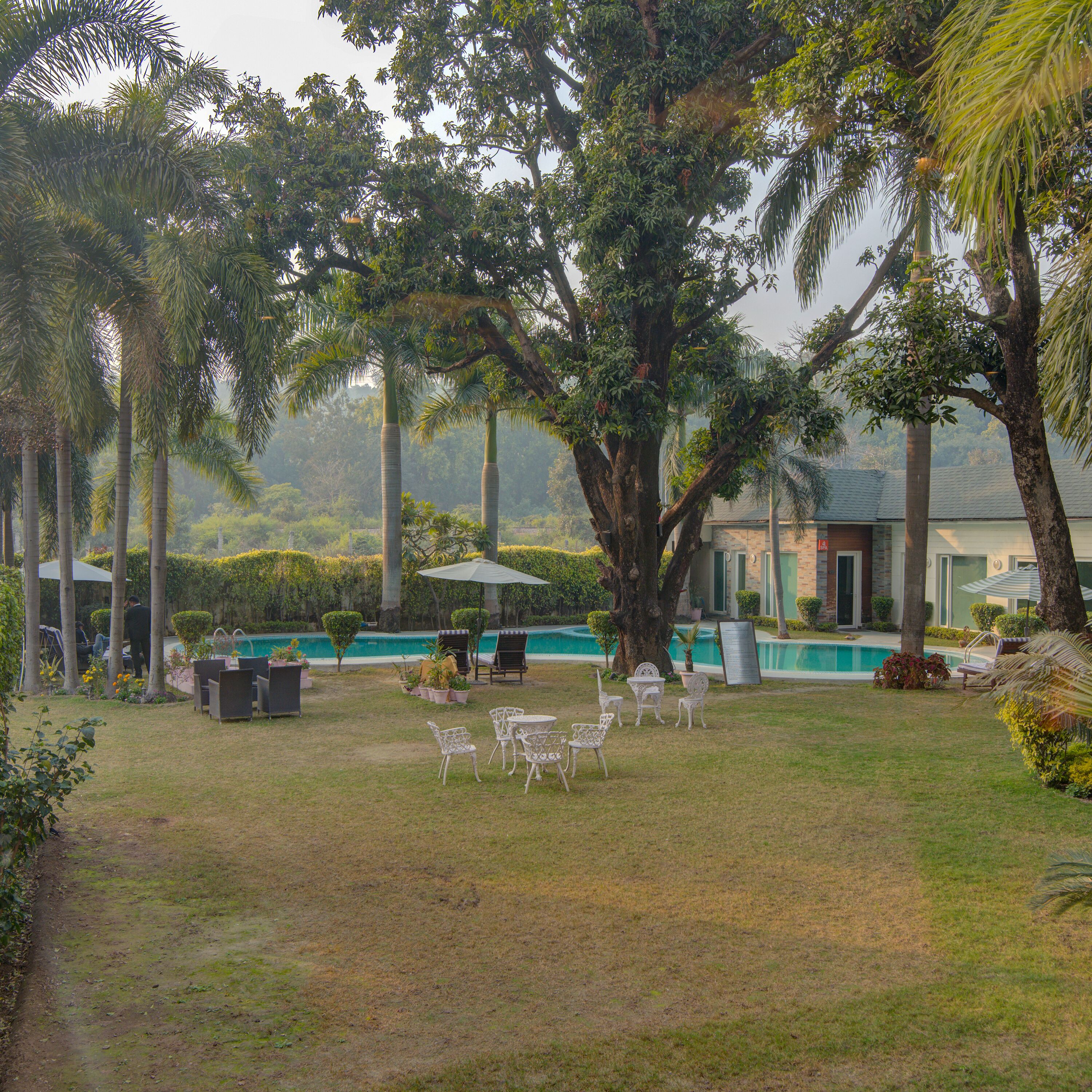 Uma área externa bem cuidada, com piscina, espreguiçadeiras e mesa de jantar.