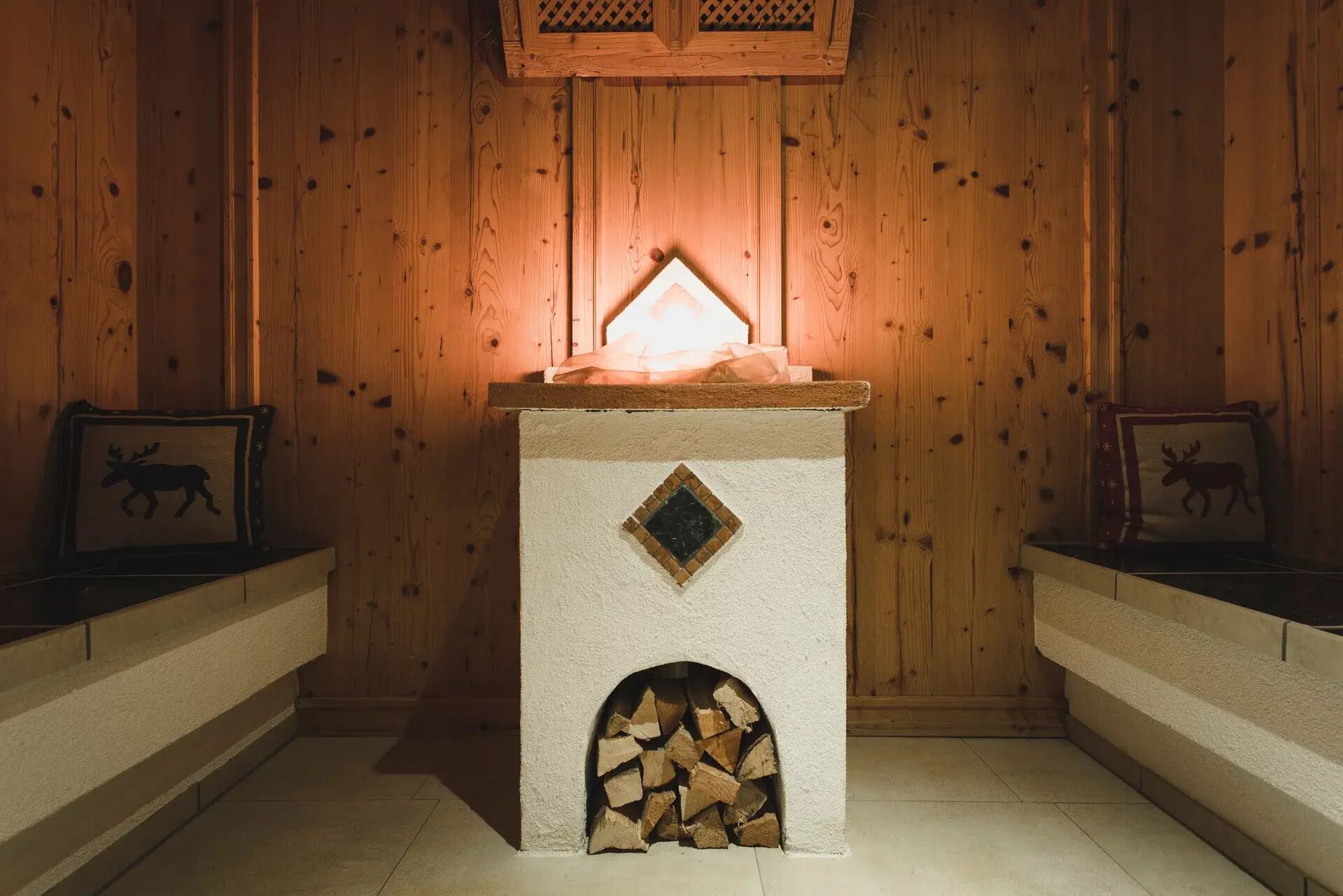 Um quarto aconchegante com paredes de madeira, lareira com manto decorativo e quadros de renas nas paredes.