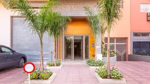 Um edifício residencial com portão de garagem, entrada para carros e placa indicando proibido estacionar.