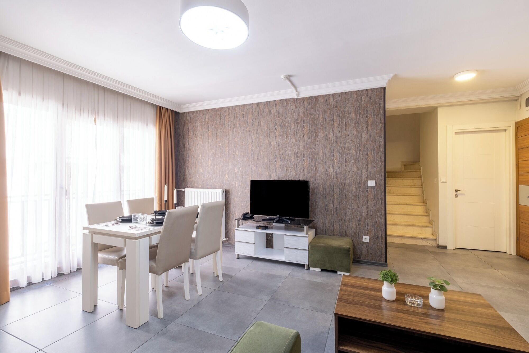 Uma sala de estar moderna com área de jantar, televisão de tela plana e escada para outro andar.