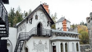 Um edifício com fachada branca, varanda com grades pretas e um brasão na parede.