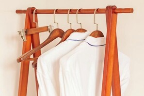 Um cabideiro de madeira com cabides pendurando camisas brancas.