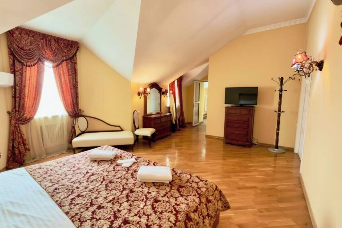 Quarto com cama, mesa de cabeceira, abajur e cômoda.