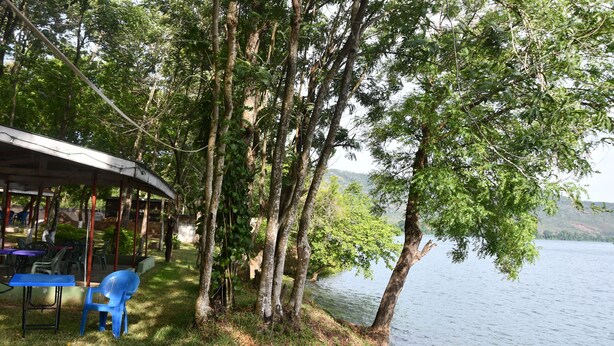 Uma área de estar à beira do lago, com cobertura, mesas e cadeiras.