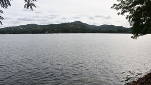 Um lago tranquilo com margem rochosa e uma cordilheira distante.