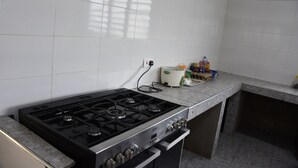 Cozinha com fogão a gás, micro-ondas e bancada com diversos objetos.